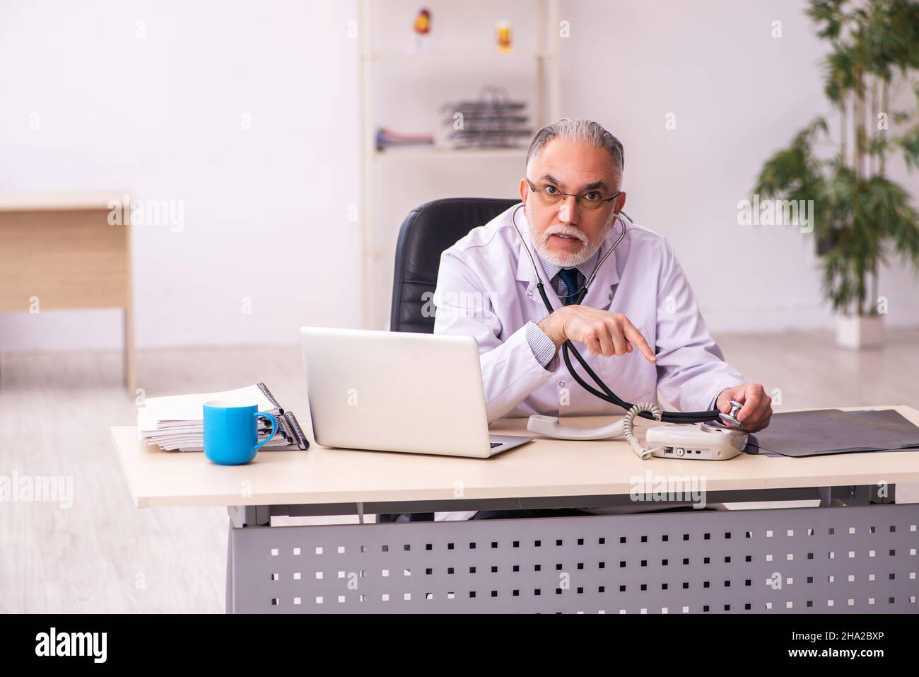 Aged male doctor working at workplace Stock Photo - Alamy