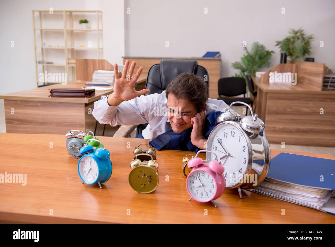 Young businessman sleeping in the office in time management concept ...
