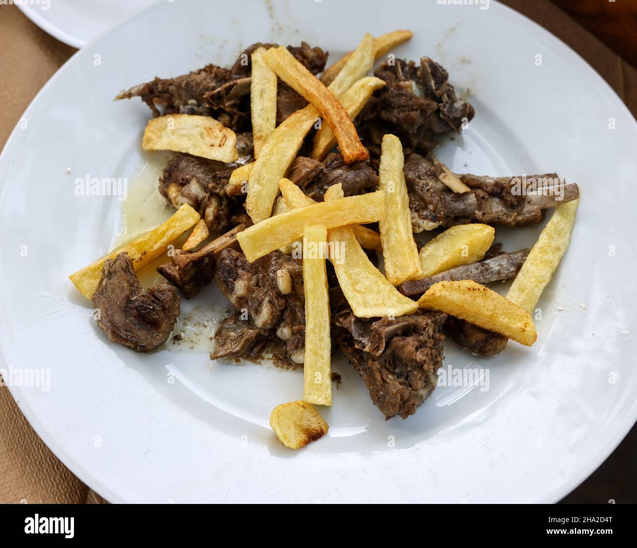 grilled goat with fries on a white plate Stock Photo - Alamy