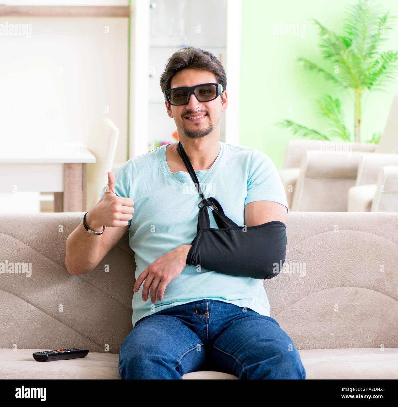 The arm injured man sitting on the sofa watching tv Stock Photo - Alamy