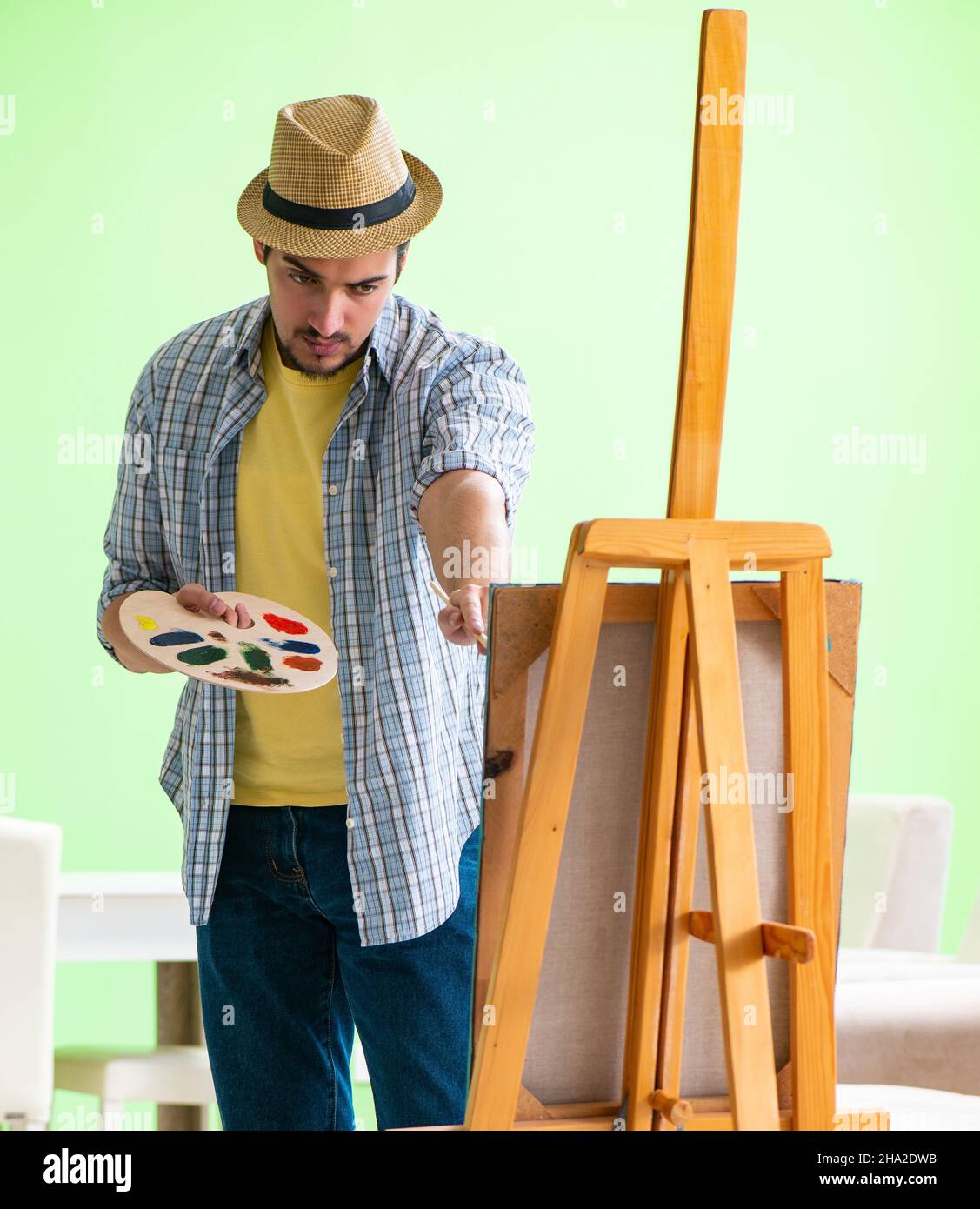 The young male artist working on new painting in his studio Stock Photo ...