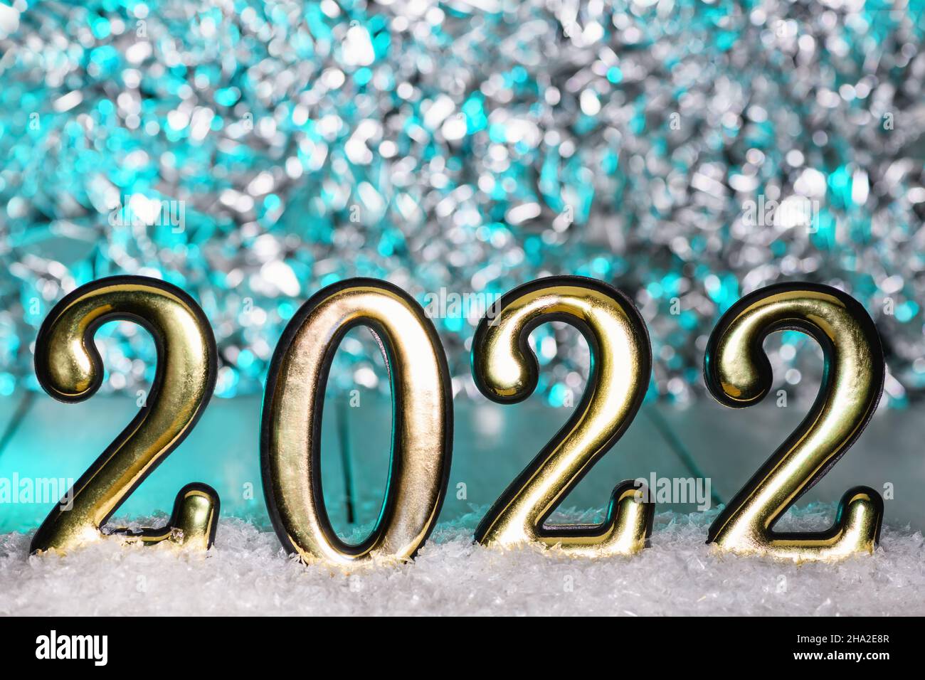 Gold numbers 2022 on snow with green backlight. New year backdrop with ...