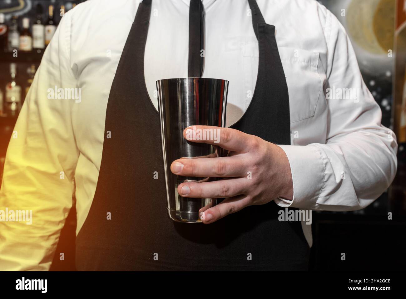 The hand of a professional bartender man holds a tool for mixing and ...