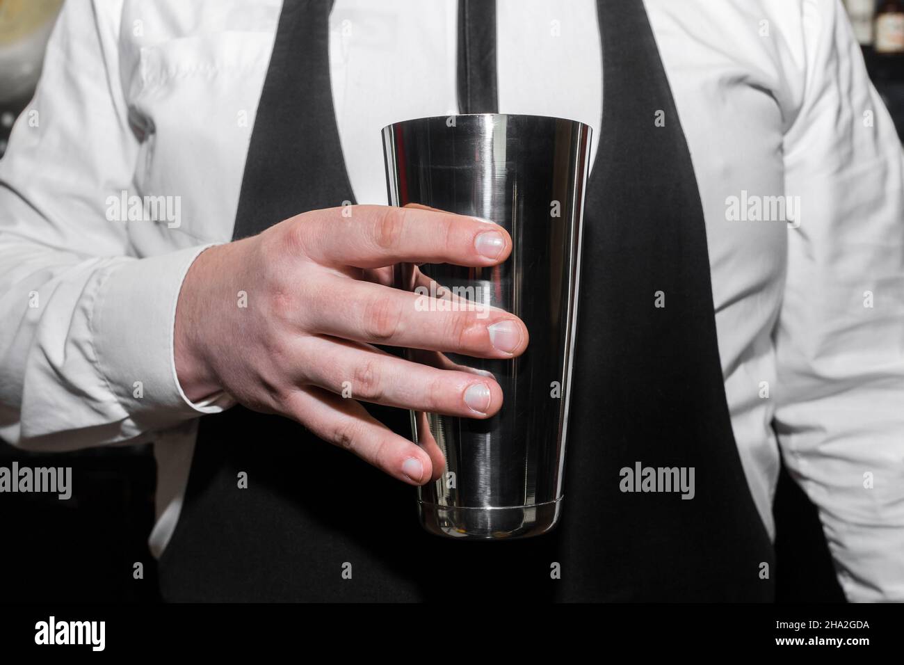 The hand of a professional bartender man holds a tool for mixing and ...
