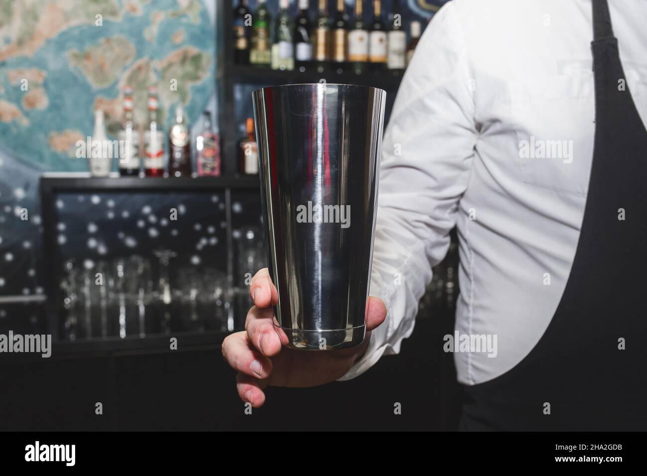 The hand of a professional bartender man holds a tool for mixing and ...