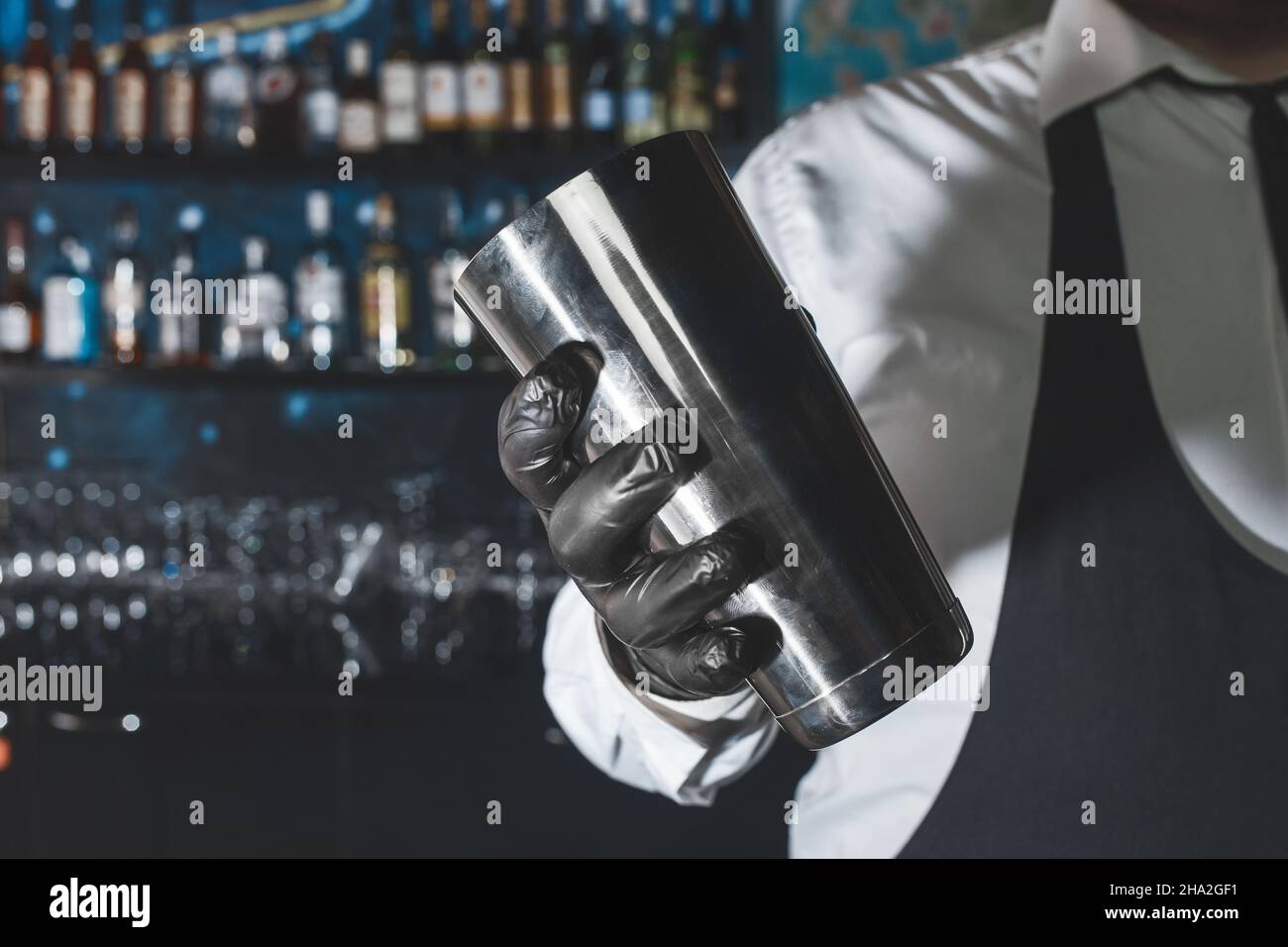 The hand of a professional bartender in a black latex glove with a bar ...