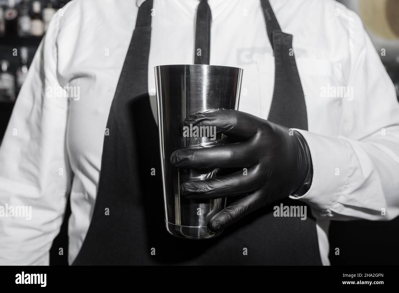 The hand of a professional bartender man in black latex glove holds a ...