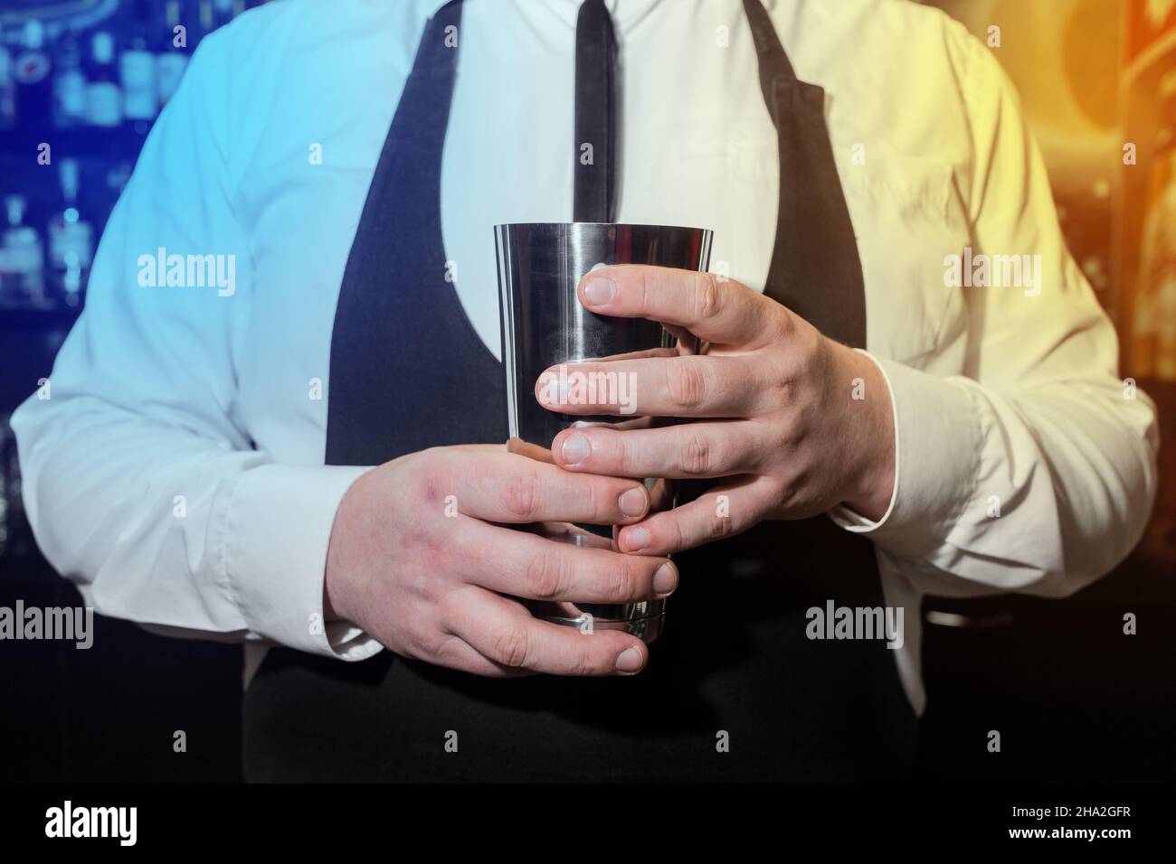 The hands of a professional bartender man holds a tool for mixing and ...