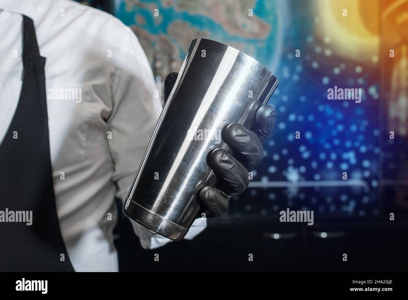 The hand of a professional bartender in a black latex glove with a bar ...