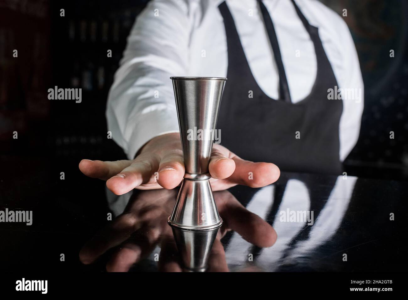 The hand of a professional bartender holds a jigger tool or measuring ...