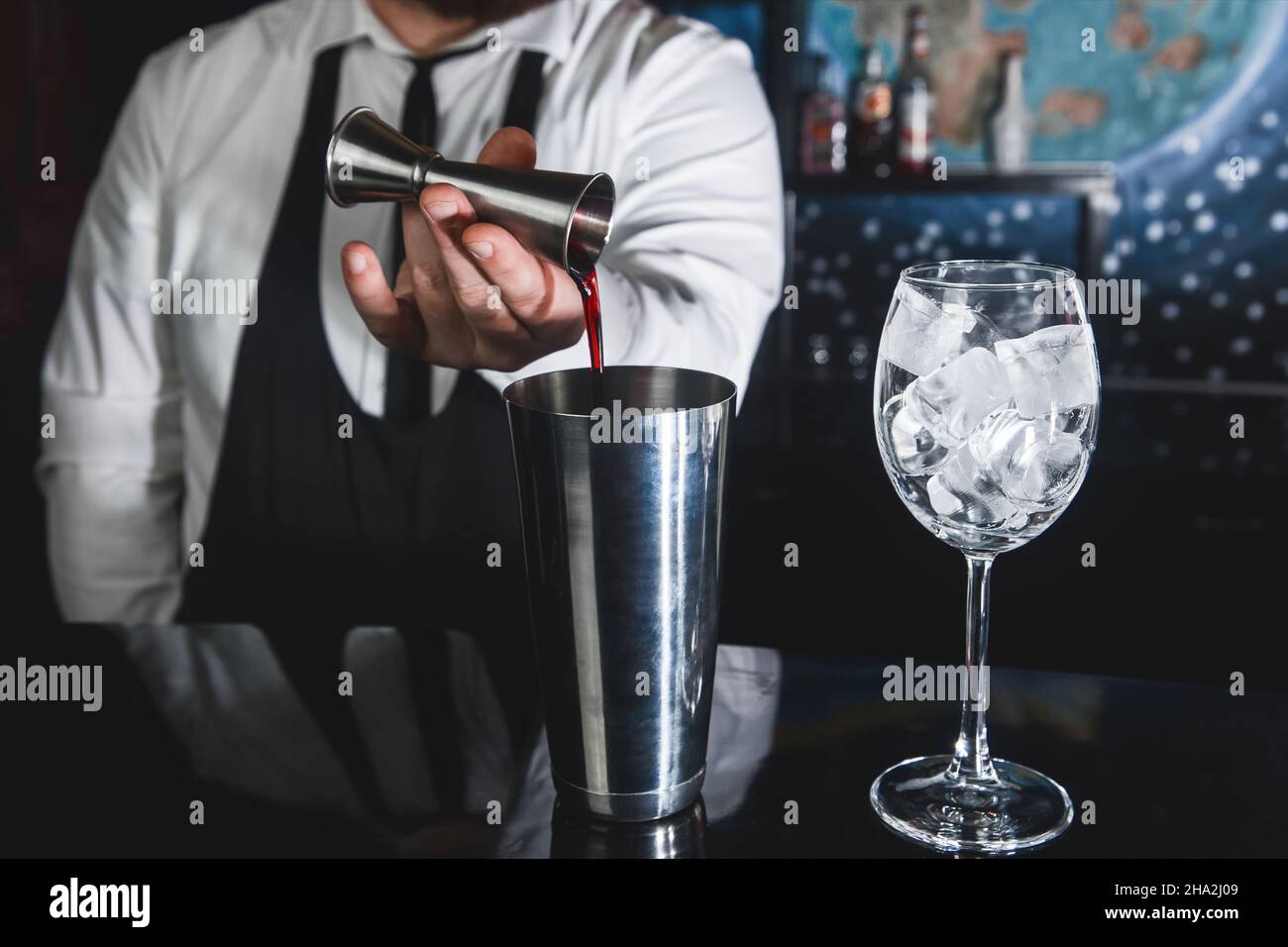 The hands of a professional bartender pour syrup into a measuring glass ...