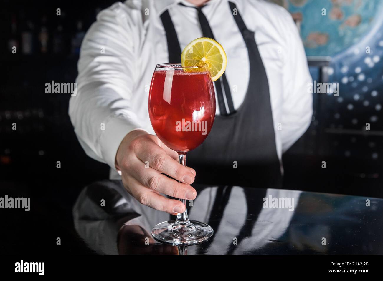 Professional bartender hand serves red alcoholic beverage in glass ...