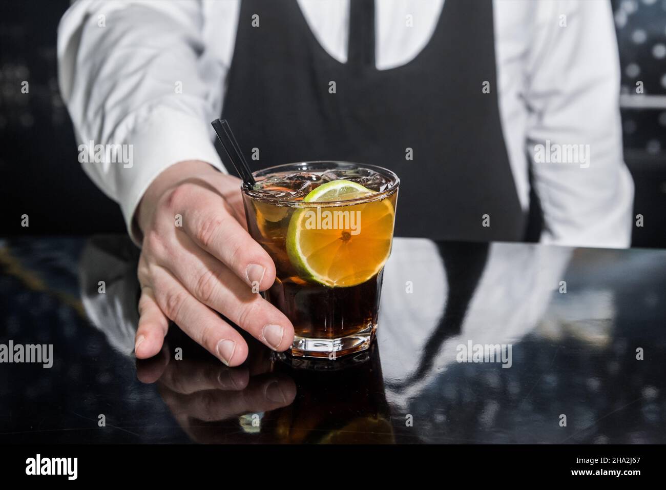 The hand of a professional bartender serves an alcoholic beverage ...