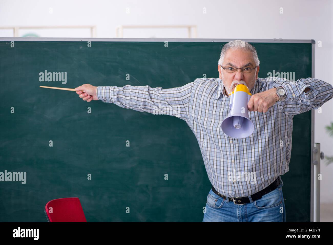 Aged male teacher holding megaphone in the classroom Stock Photo - Alamy