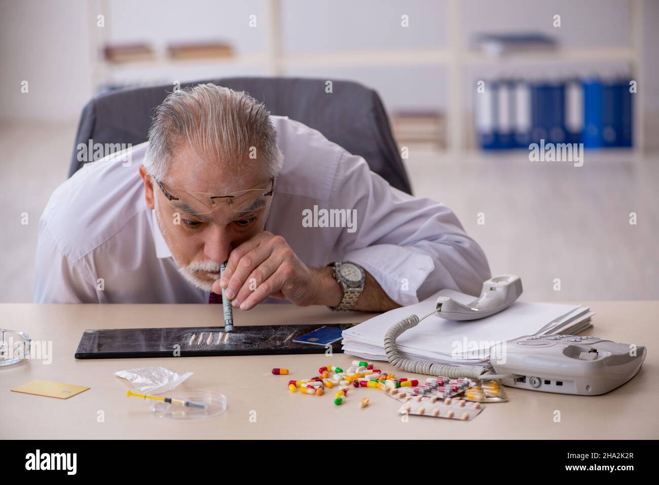 Old male drug addicted employee sitting at workplace Stock Photo - Alamy