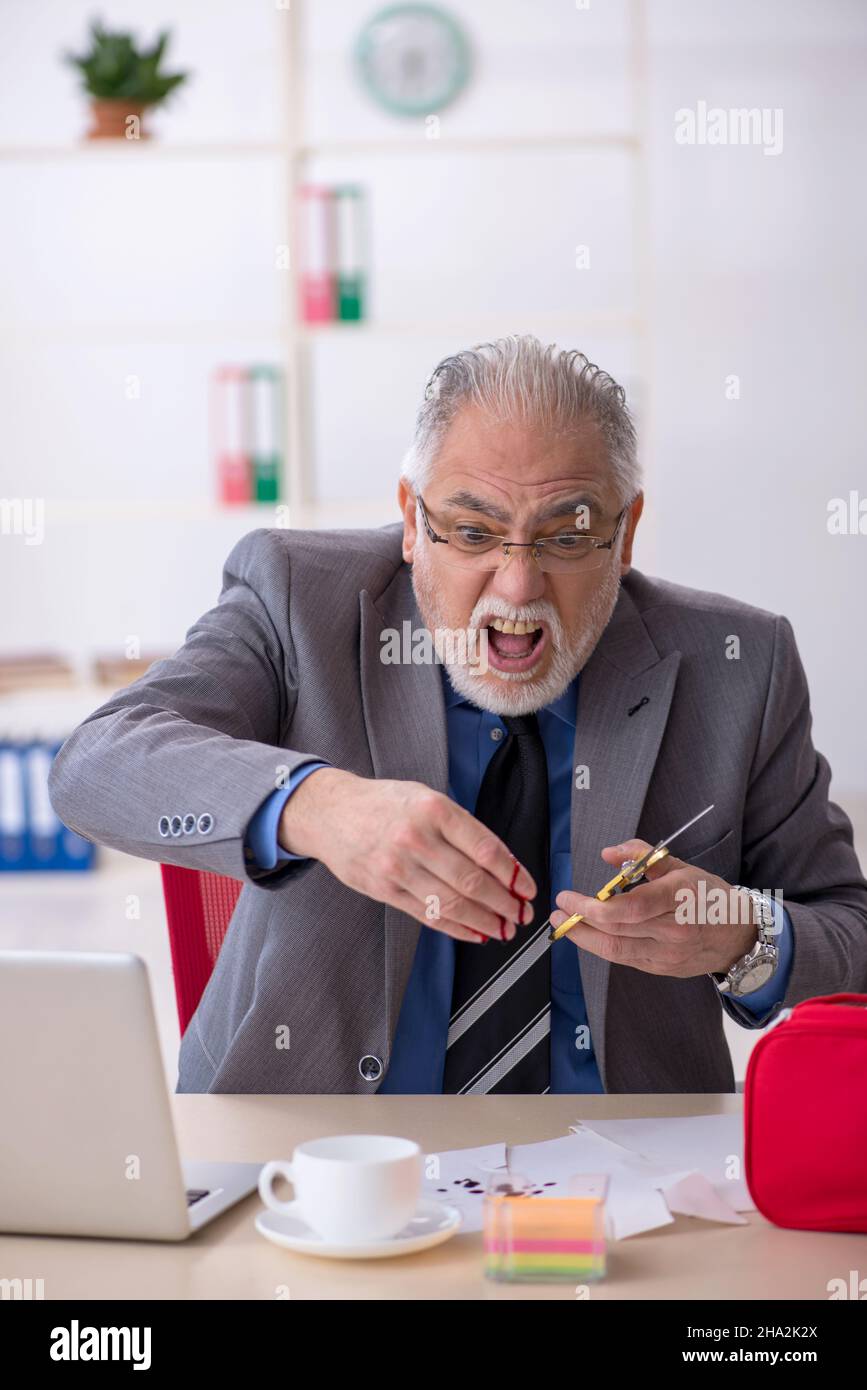 Old businessman employee cutting his hand at workplace Stock Photo - Alamy