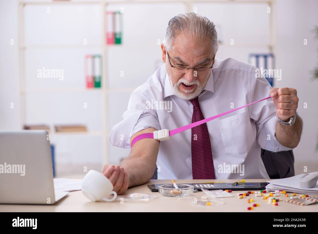 Old male drug addicted employee sitting at workplace Stock Photo - Alamy