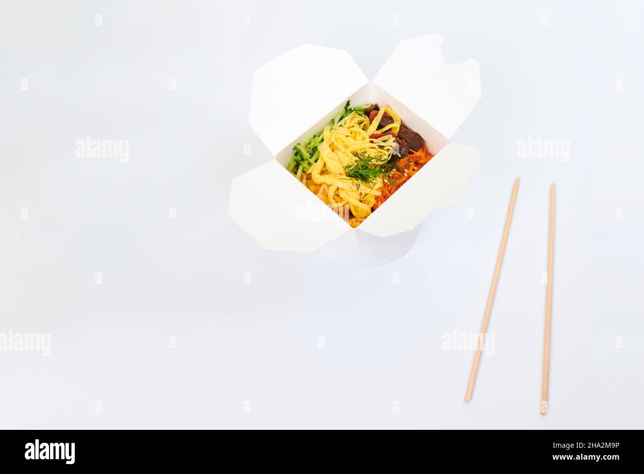 Rice wok with seafood and vegetables in white box and wooden chopsticks ...