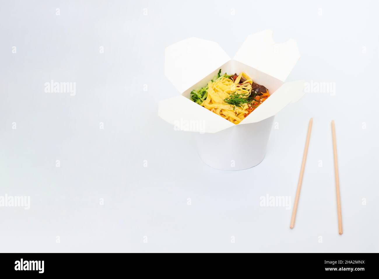 Rice wok with seafood and vegetables in white box and wooden chopsticks ...