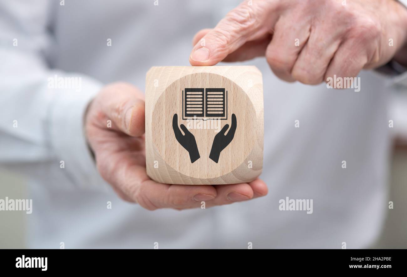 Hand holding a wooden cube with symbol of knowledge concept Stock Photo ...
