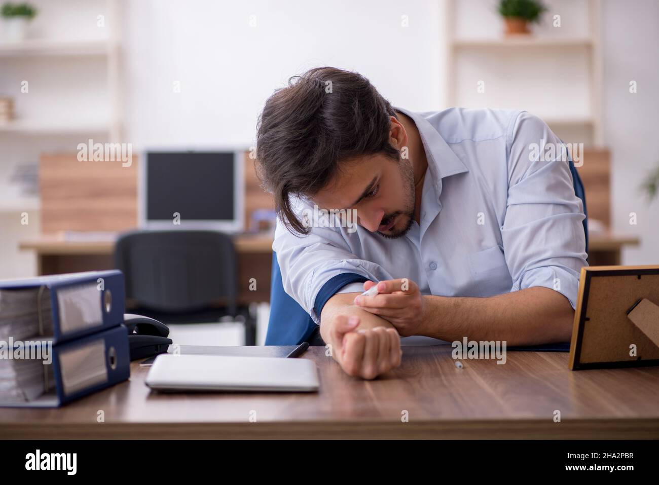 Young male drug addicted employee in the office Stock Photo - Alamy