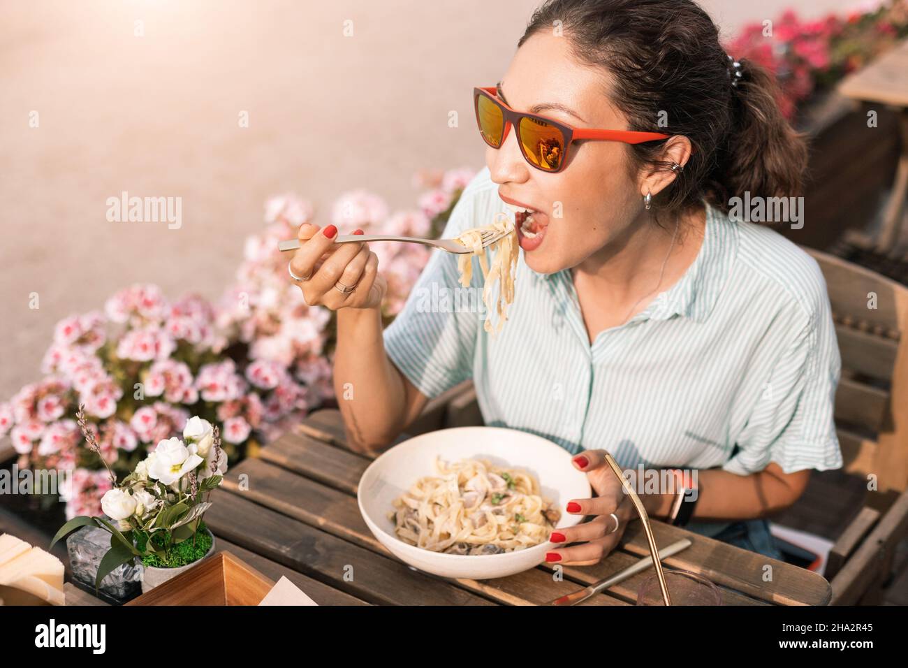 Happy asian woman eating itallian spaghetti or pasta outdoors in open ...