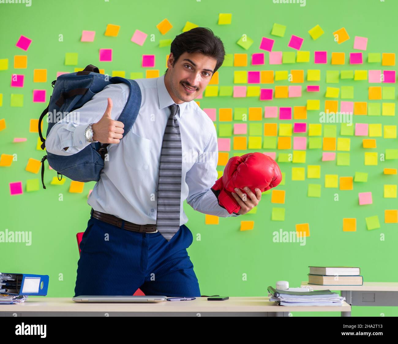 Man with boxing gloves in the office with many conflicting priorities ...