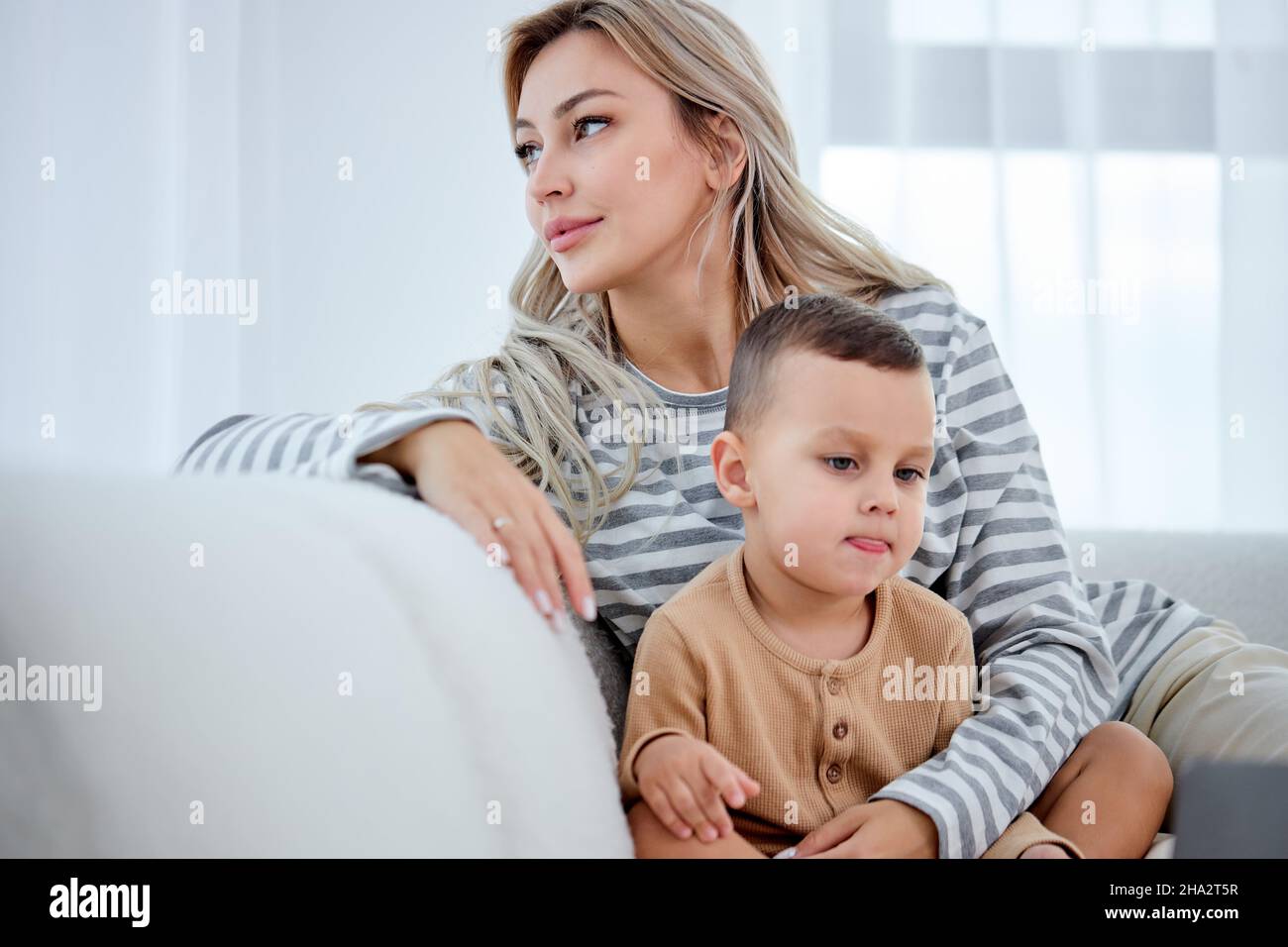 Carefree female parent has rest with preschooler son in living room on ...