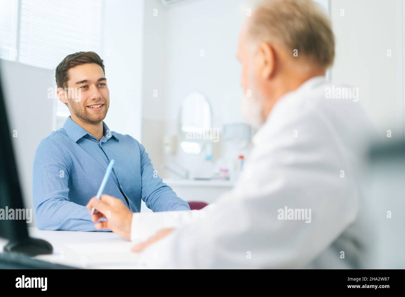 View from back to happy young man patient listening senior male doctor ...