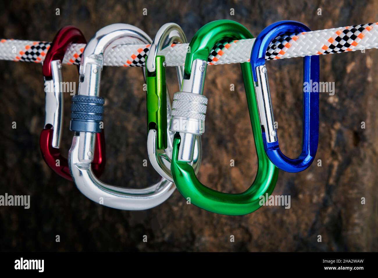 five carabiners hanging on a rope on a rock face Stock Photo - Alamy