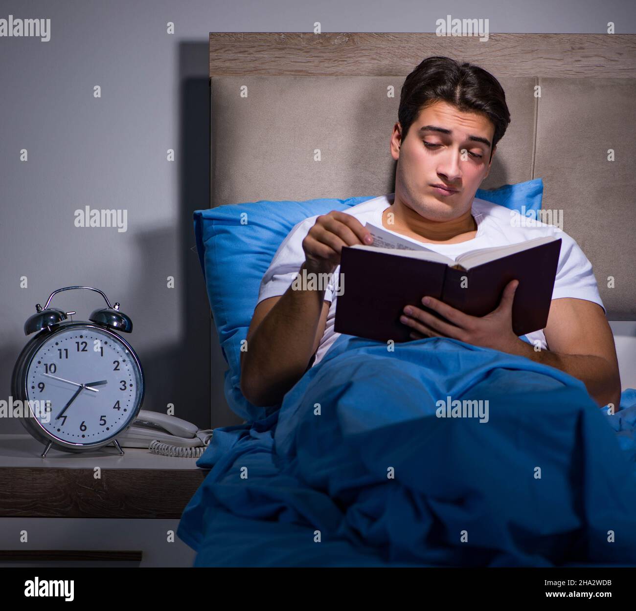 The young man reading book in bed Stock Photo - Alamy