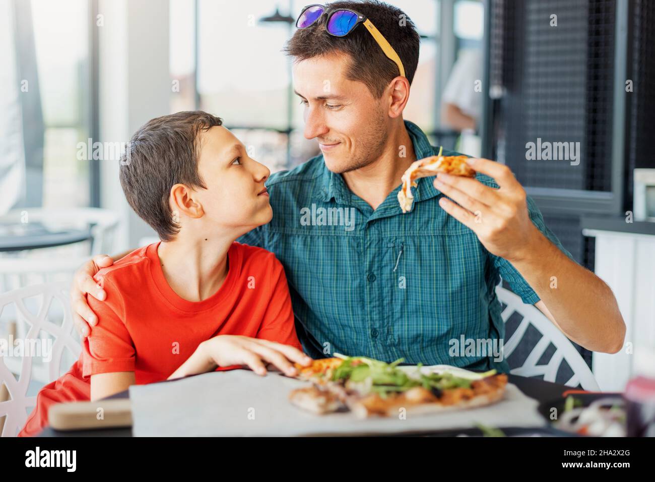 A young dad enjoys fatherhood and eats pizza in a fast food cafe with ...