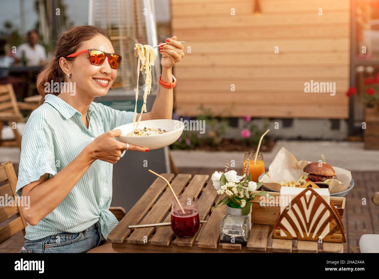 Happy asian woman eating itallian spaghetti or pasta outdoors in open ...