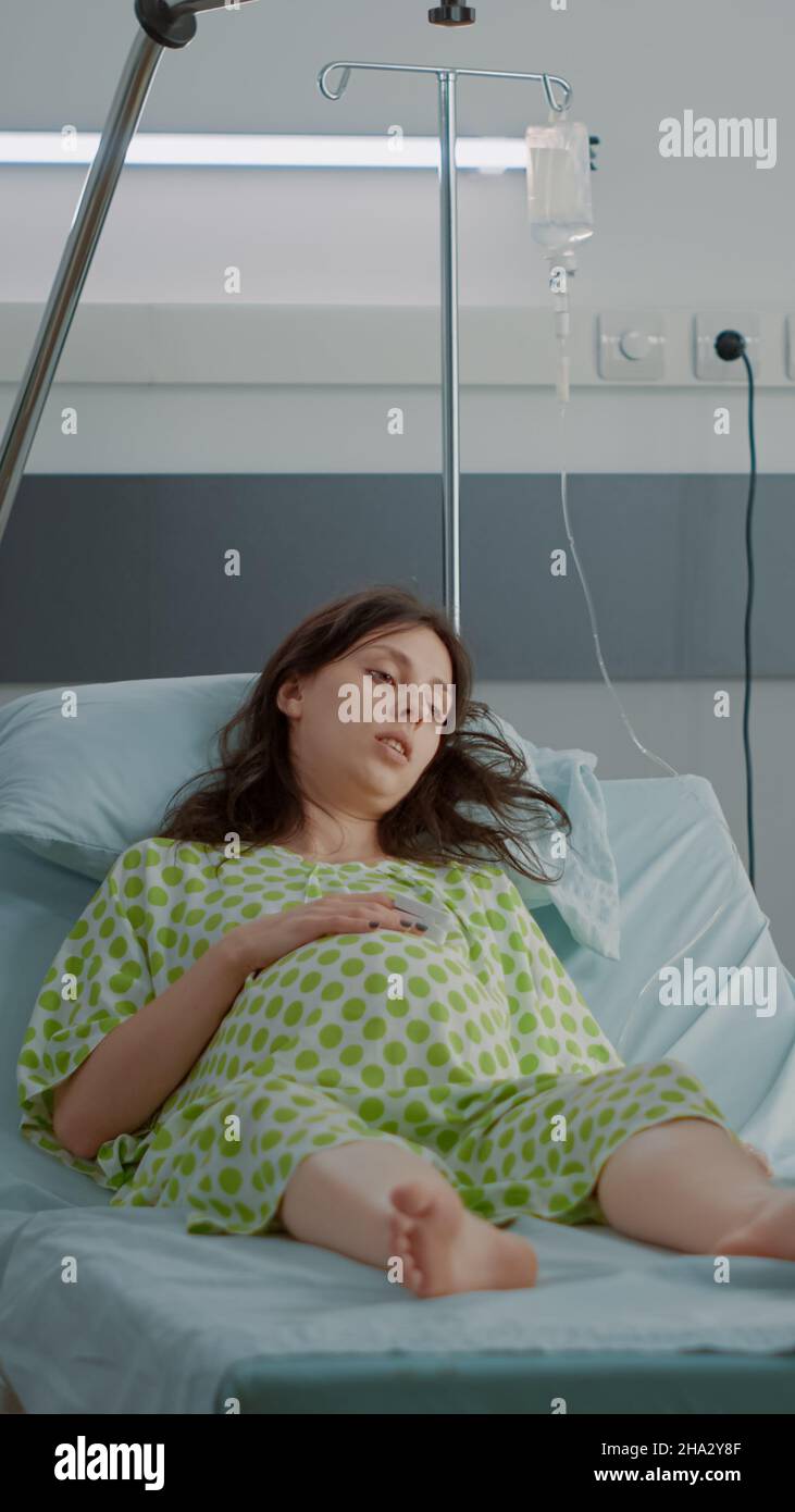 Pregnant woman laying in hospital ward bed waiting on assistance for ...