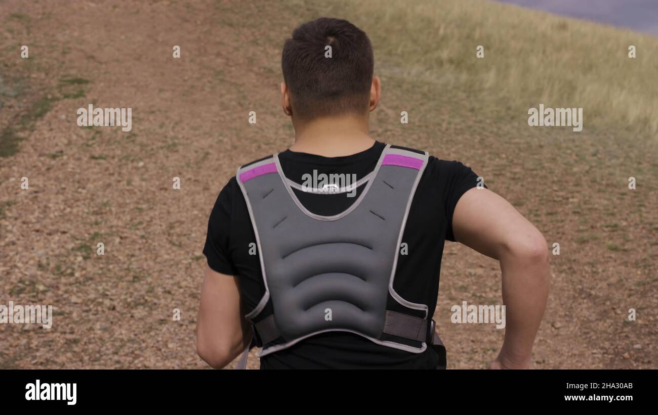 Caucasian male runner runs up steep dusty trail in dry mountains ...