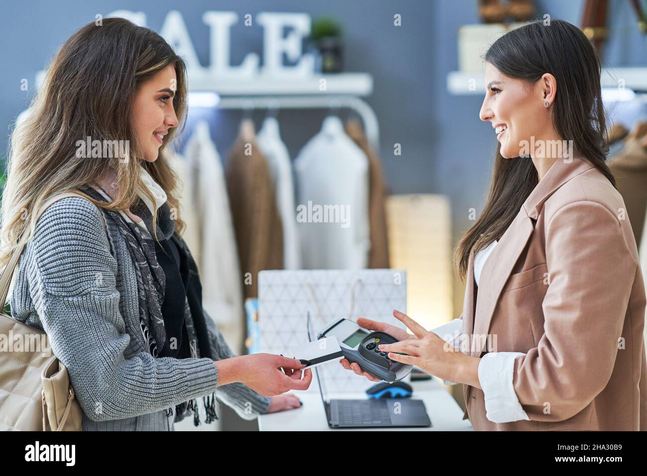 Woman seller and buyer in clothes store Stock Photo - Alamy