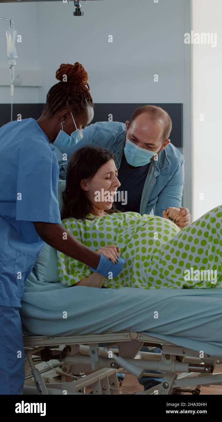 Pregnant woman giving birth in hospital ward bed with obstetrics doctor ...