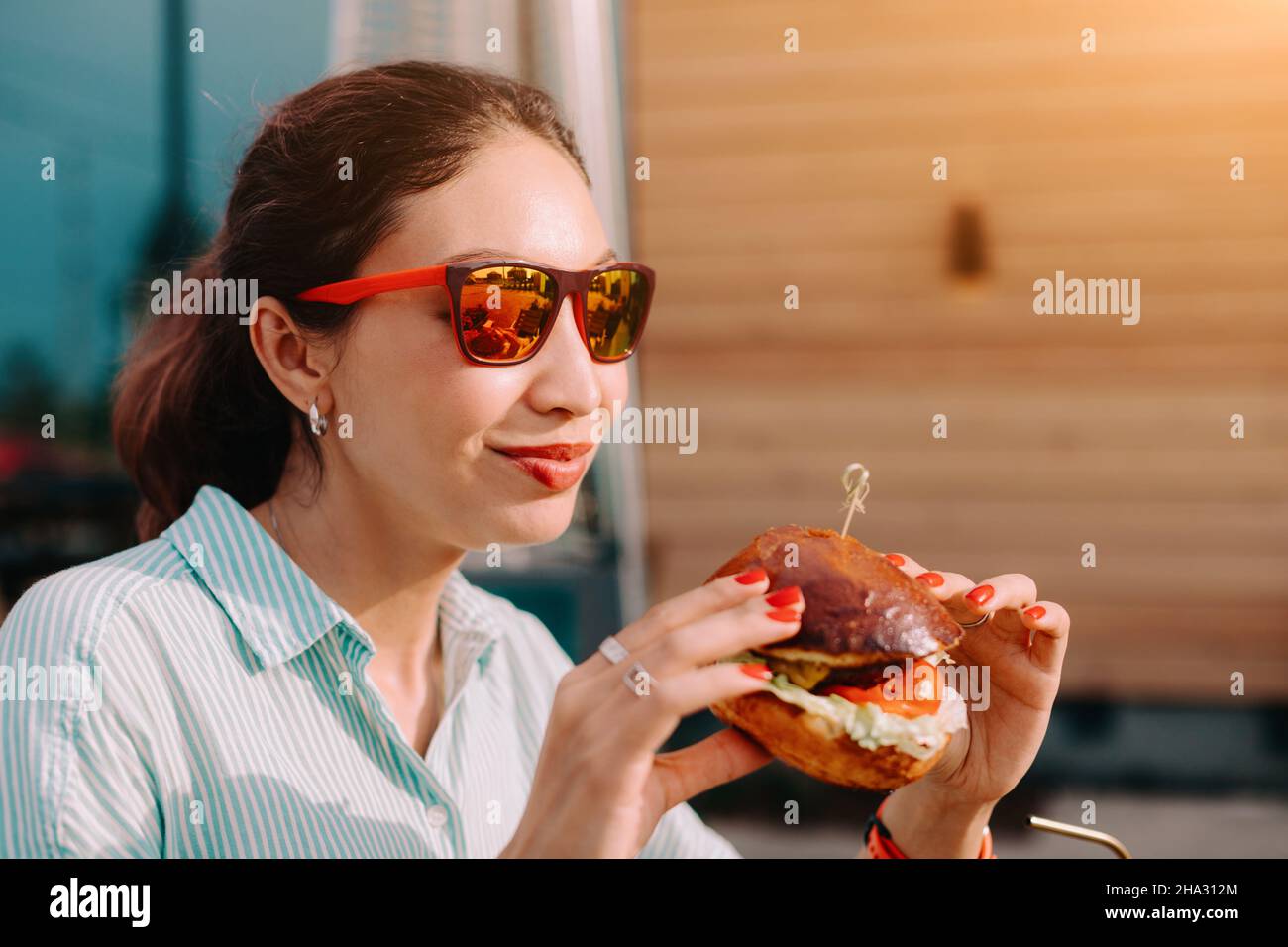 Happy asian young woman eating delicious fastfood burger in street food ...