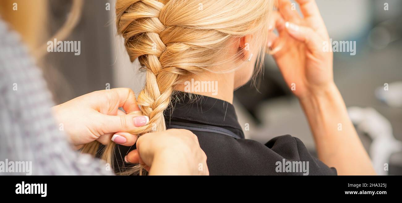 Braiding braid. Hands of female hairdresser braids long braid for a ...