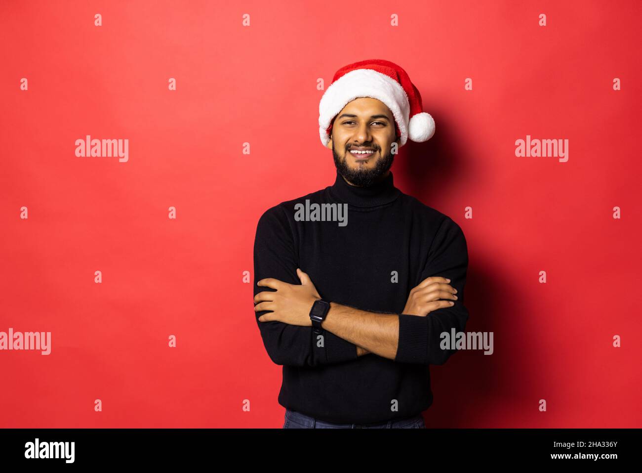 Young man wearing christmas hat for santa on red background Stock Photo ...