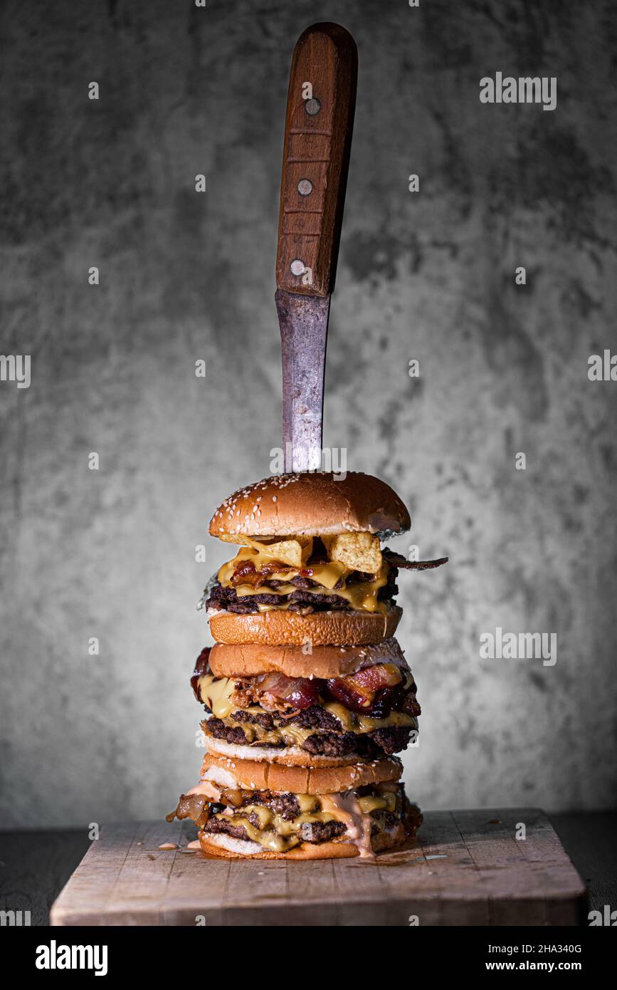 Vertical shot of a stack of gourmet burgers with a knife through them ...