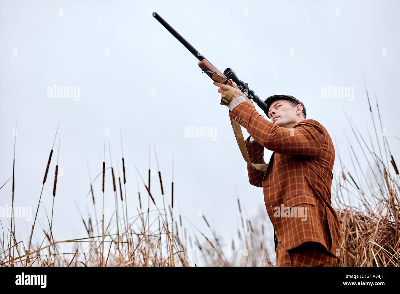confident hunter wearing brown trendy suit and hat waiting for the bird ...