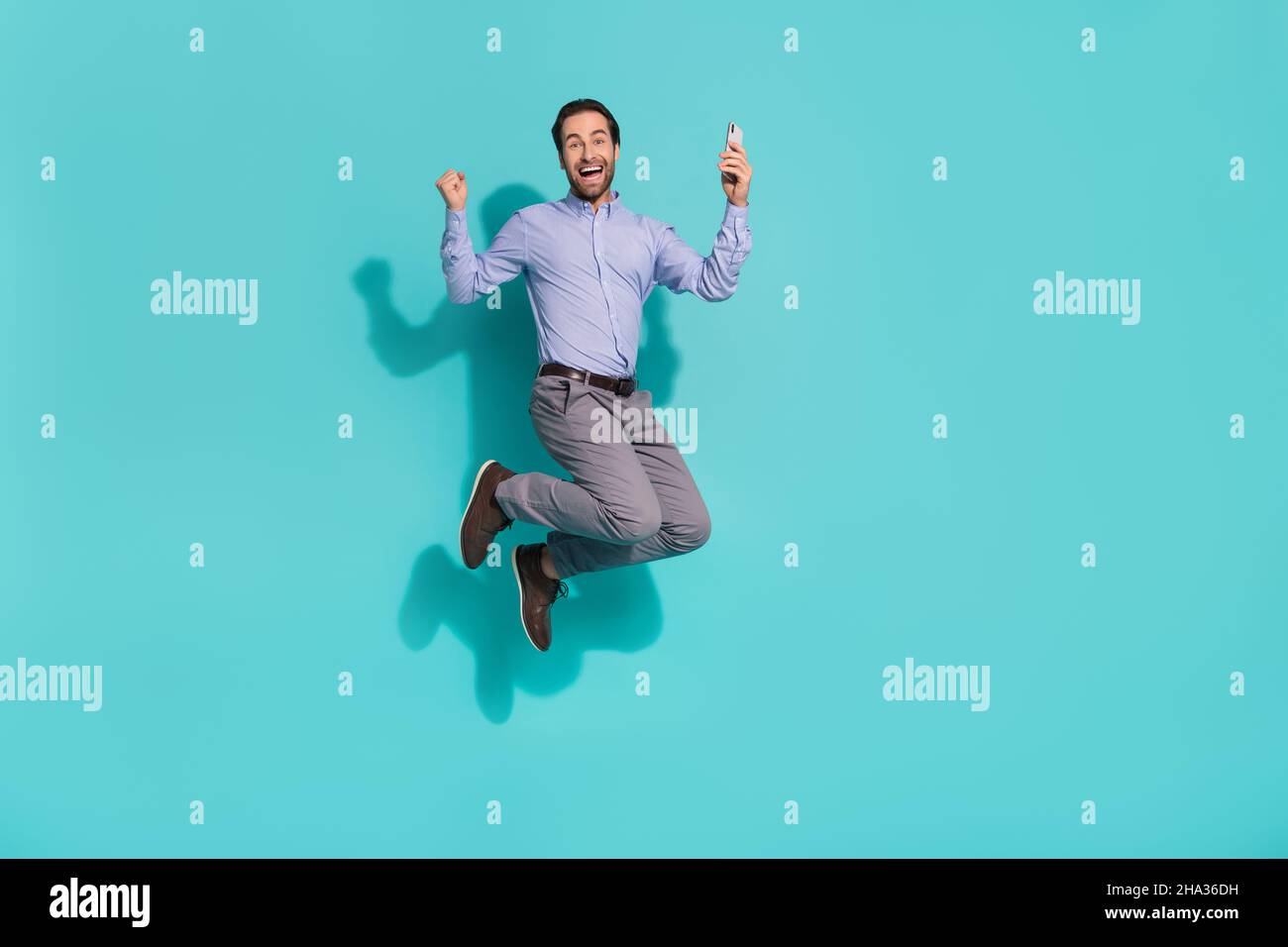 Photo of crazy funny agent man jump hold telephone rejoice wear violet ...