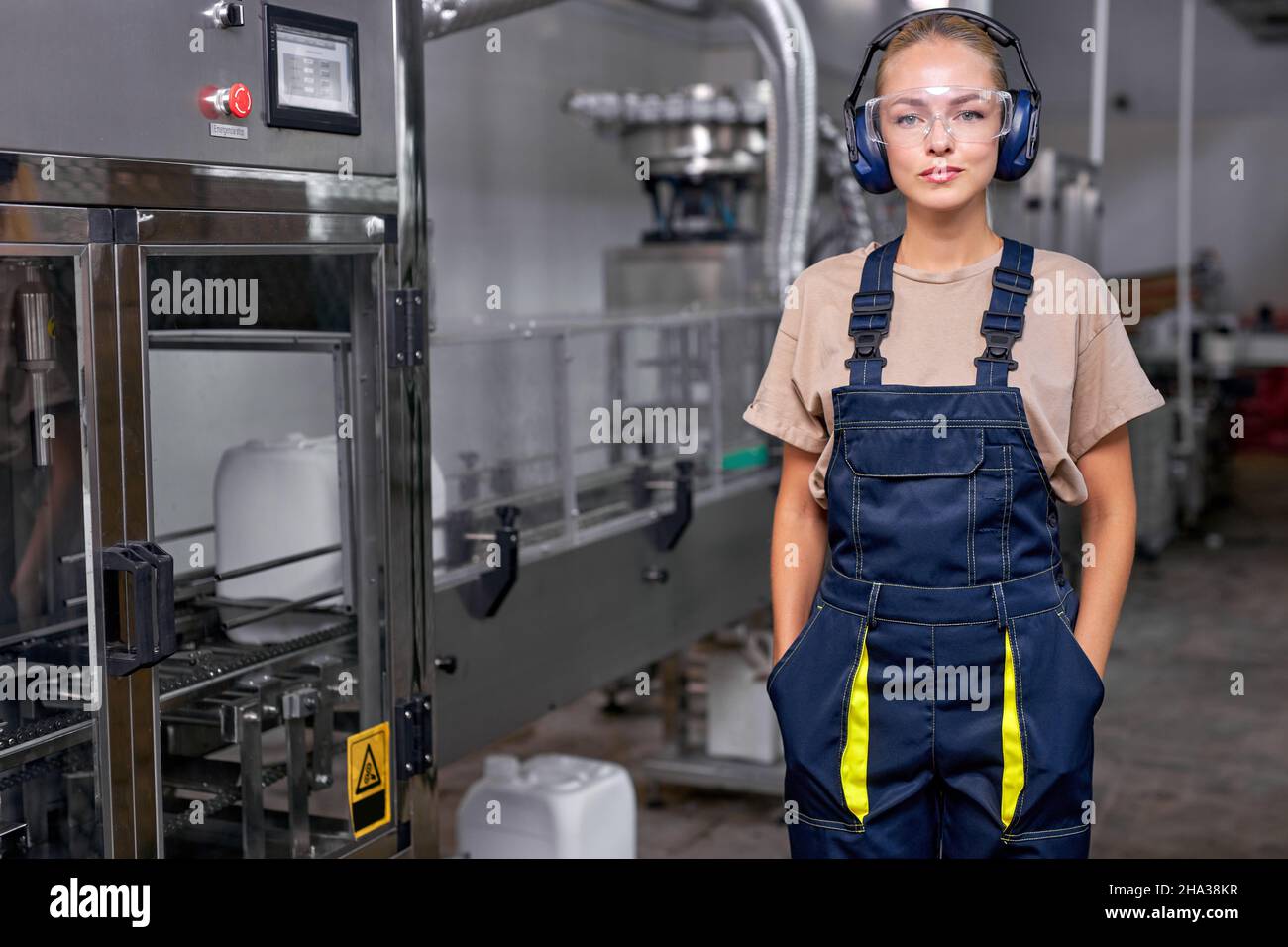 young industrial woman engineer in spectacles standing in factory at ...