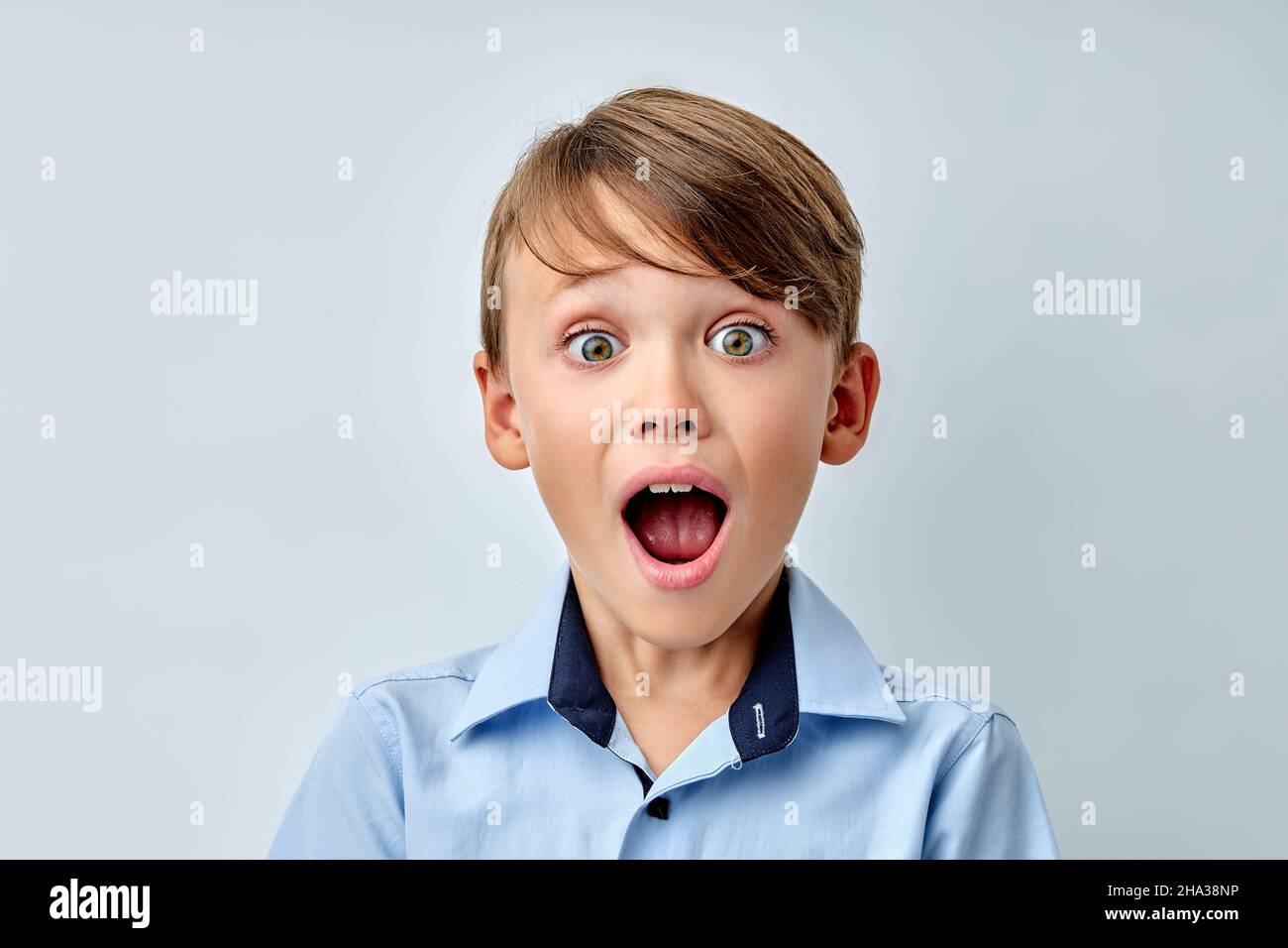 caucasian little boy amazed by news with opened mouth isolated gray ...