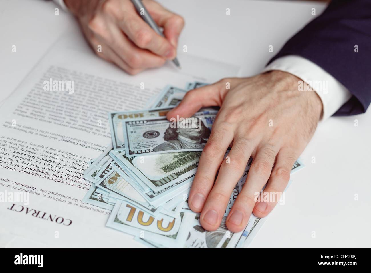 Man in suit signing contract and hold hand on money Stock Photo - Alamy