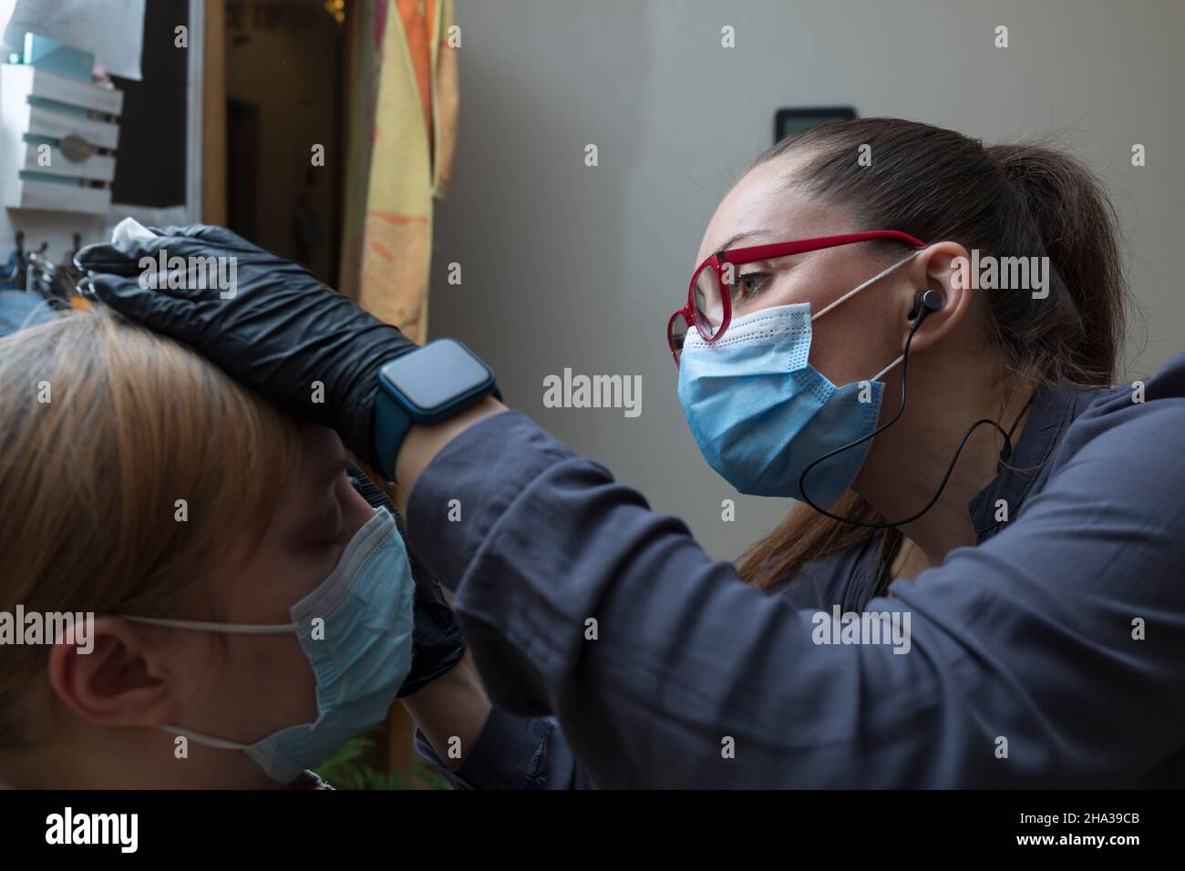 master paints the eyebrows of a client at home during a pandemic ...