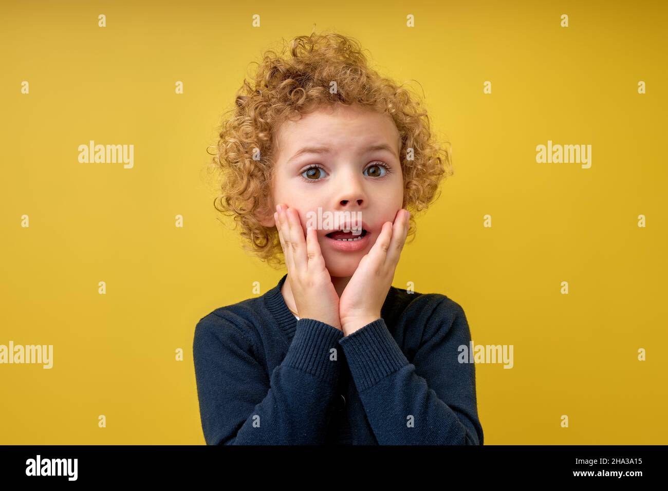 Portrait of surprised child boy in shock, touching cheeks, stand with ...