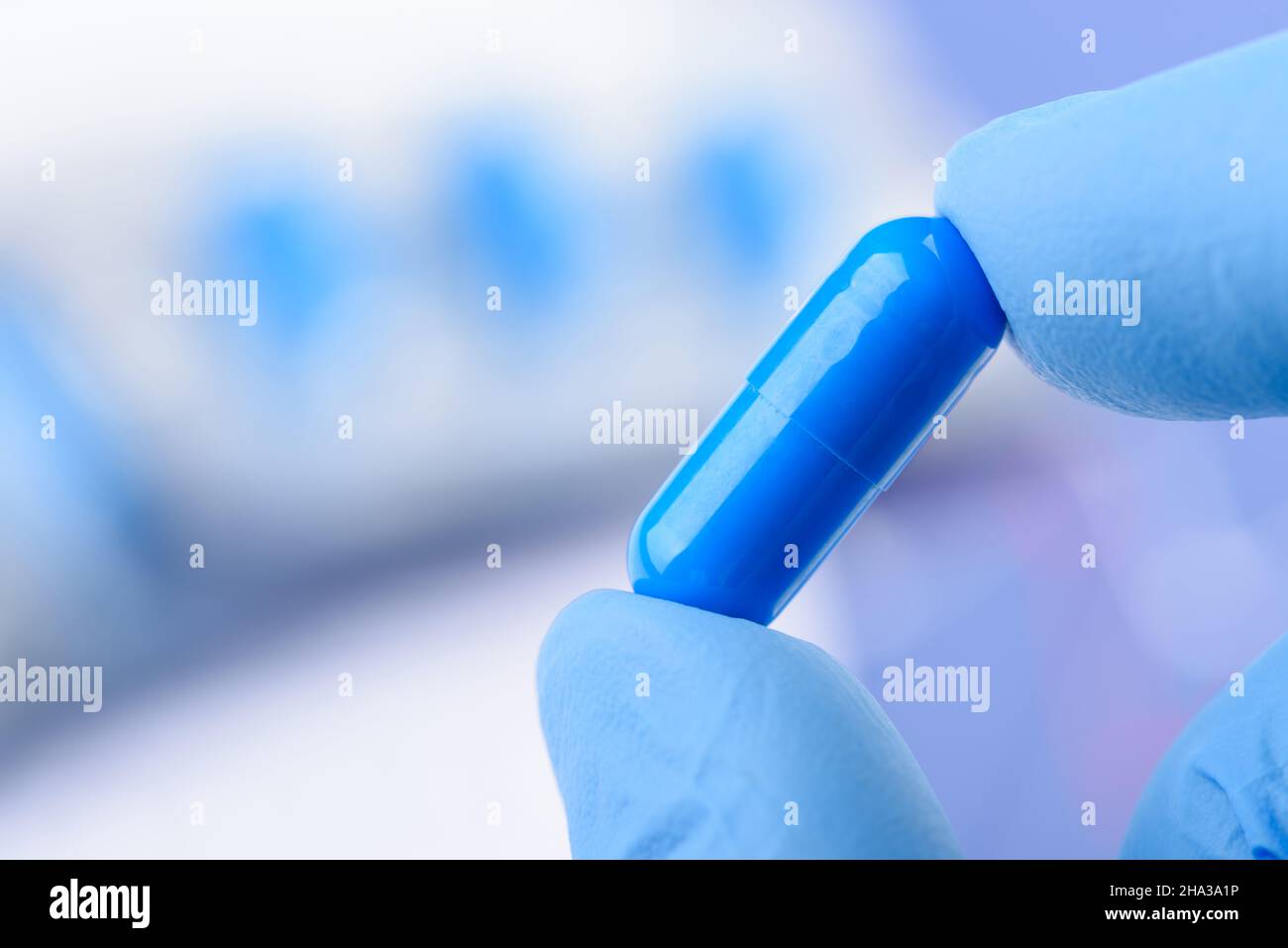 Scientist hold in fingers blue pill capsule. New medical treatment or ...