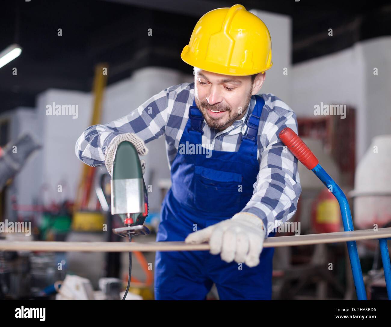 Adult guy is using power jigsaw for construction work Stock Photo - Alamy